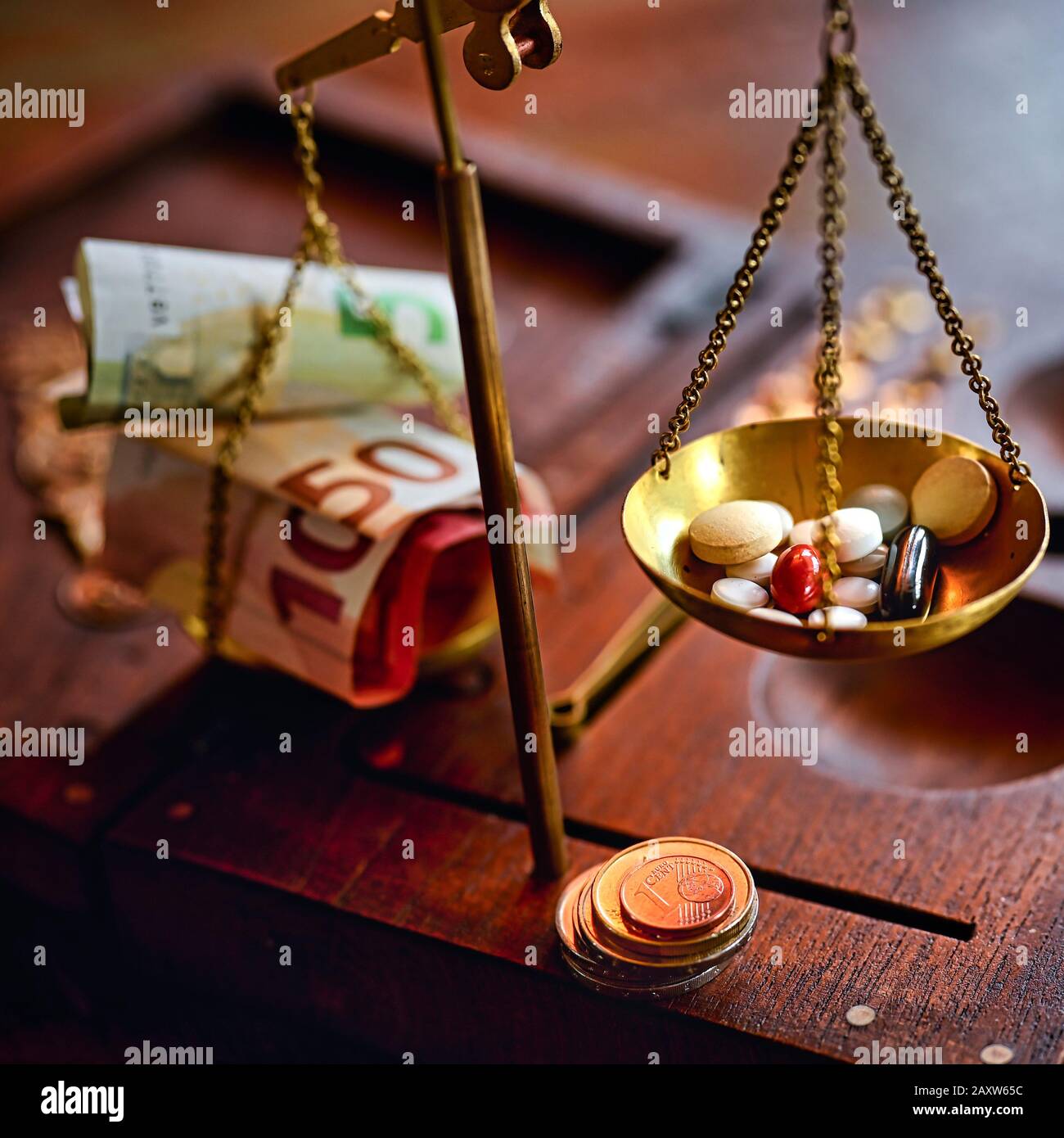 An old scale with money on one side and tablets on the other as a ...