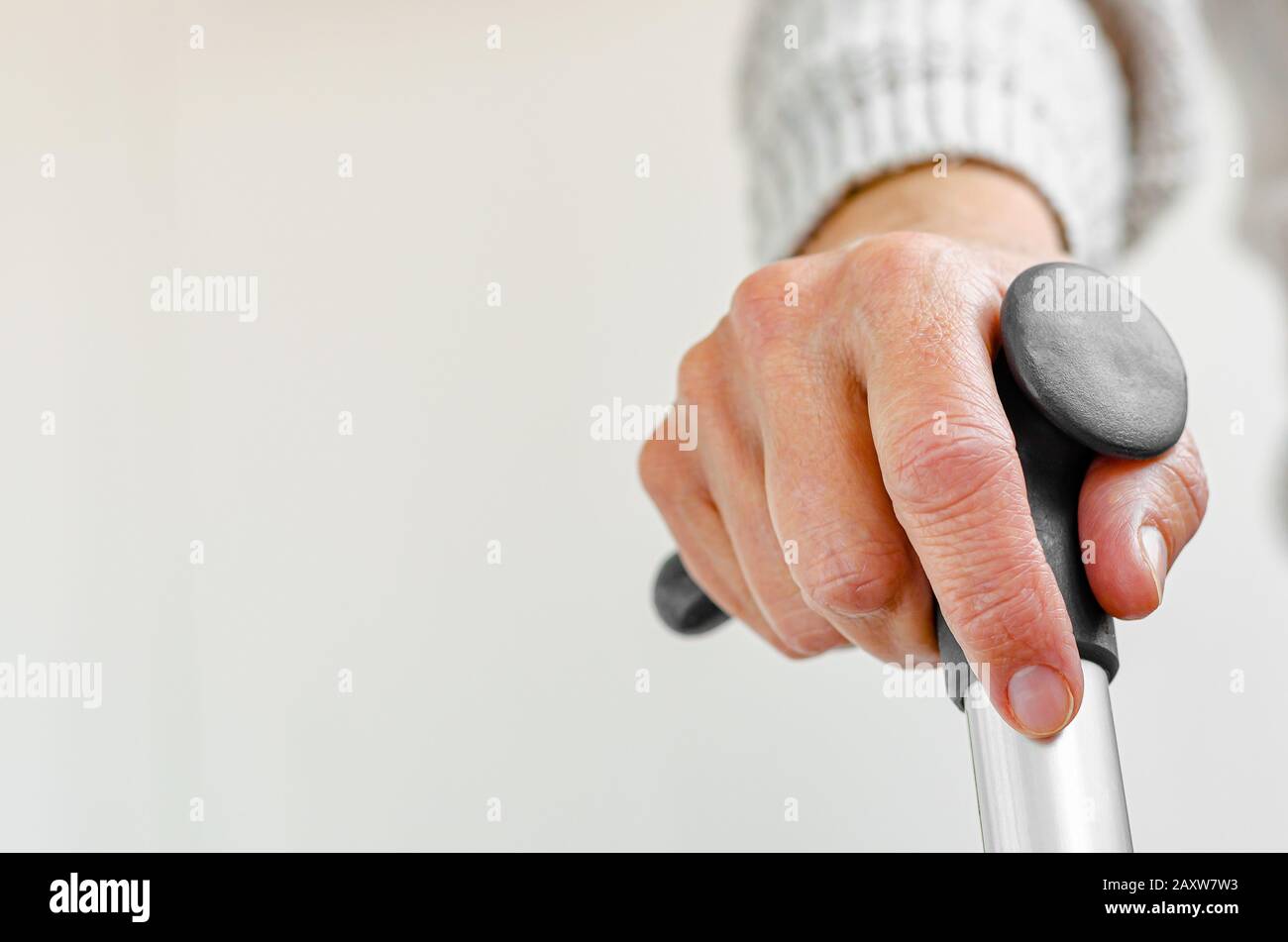 Retired woman holding metal walking stick in hand. Medical and ...