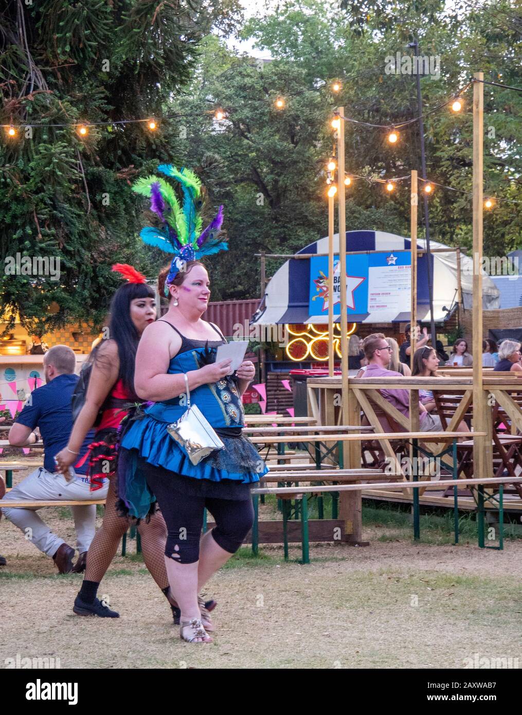 Two women dressed burlesque walking past outdoor food and beverage ...