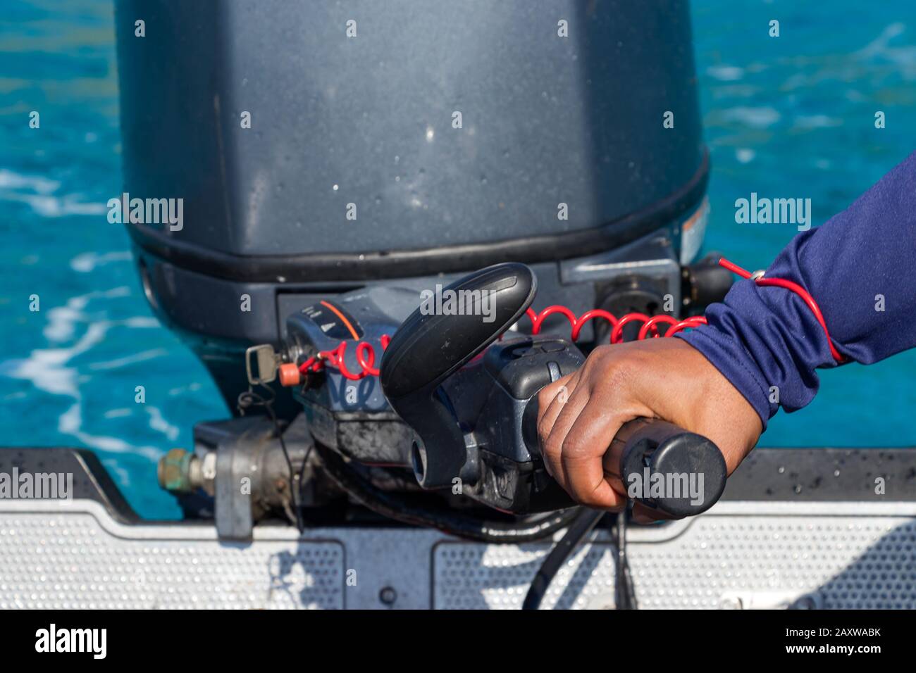 Male hand driving a inflatable boat holding the tiller of an outboard ...