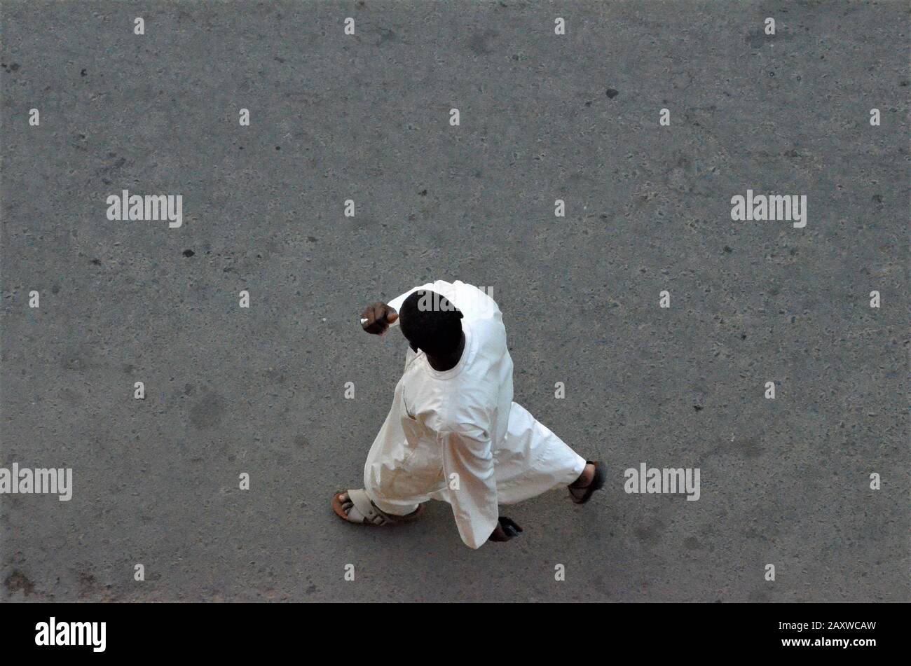 African man walking in Dakar, Senegal, wearing a traditional white ...