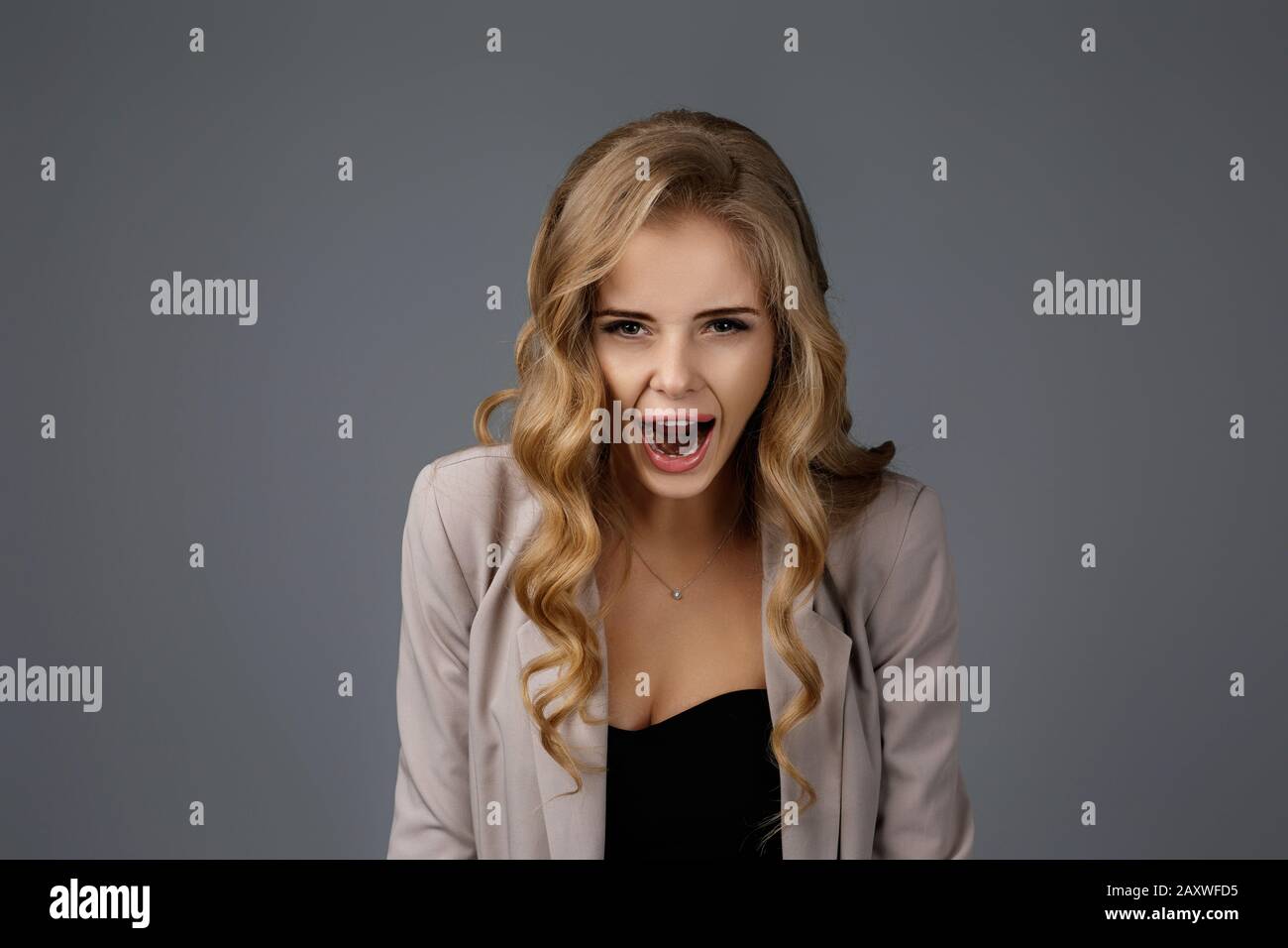 Portrait of young angry woman screaming on gray background Stock Photo ...