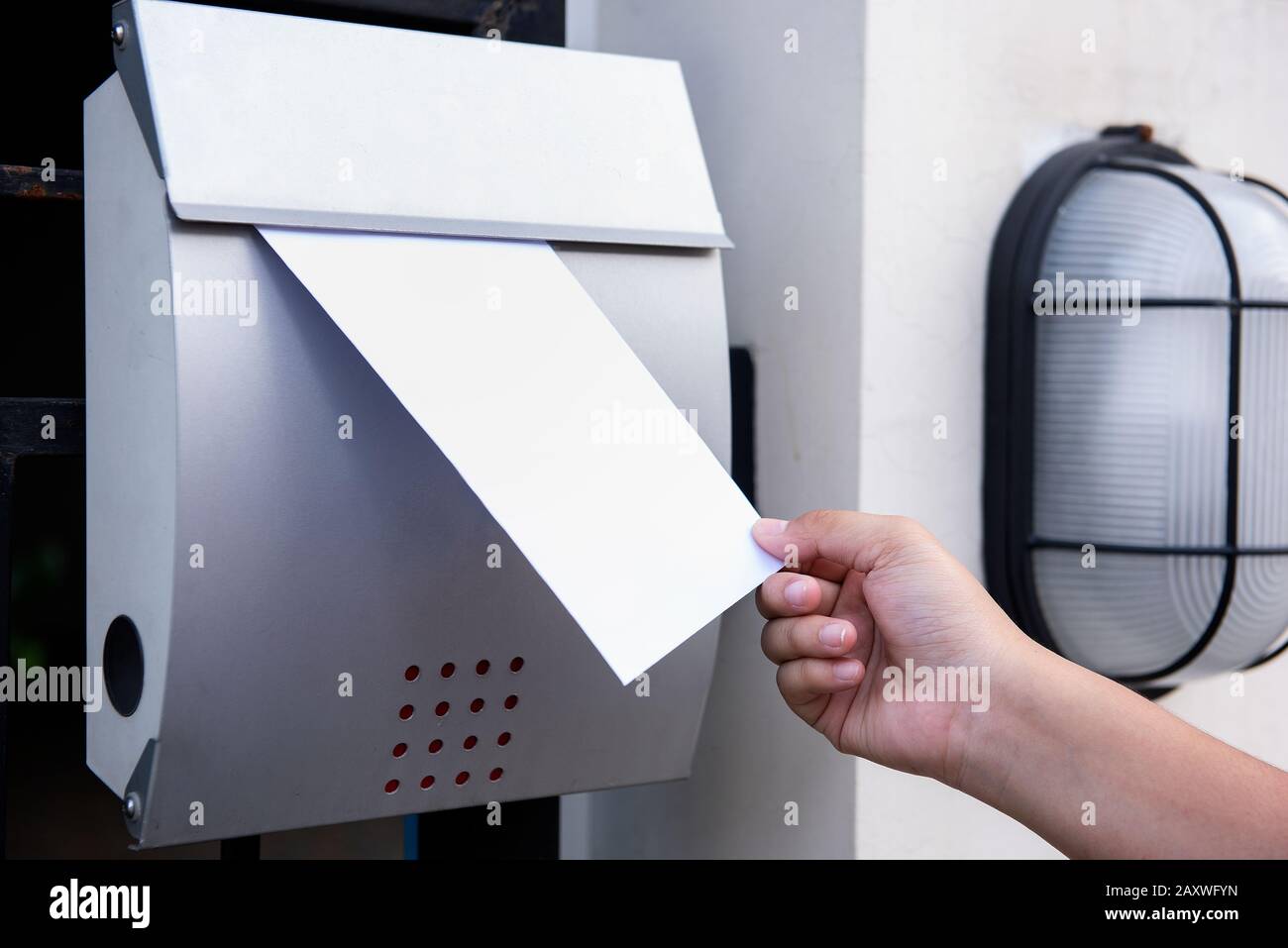 Hand inserting letters in mailbox Stock Photo - Alamy