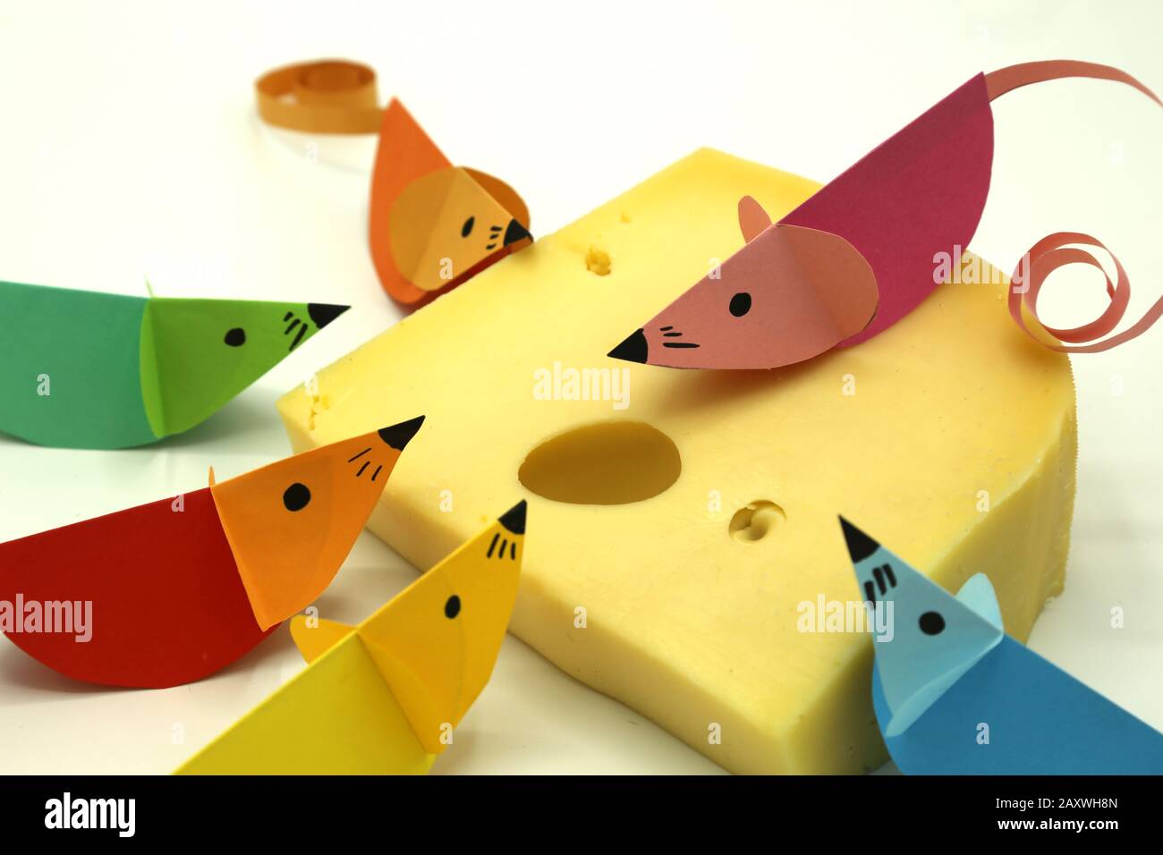 Colorful origami mice with curly tail on a big slice of cheese isolated ...