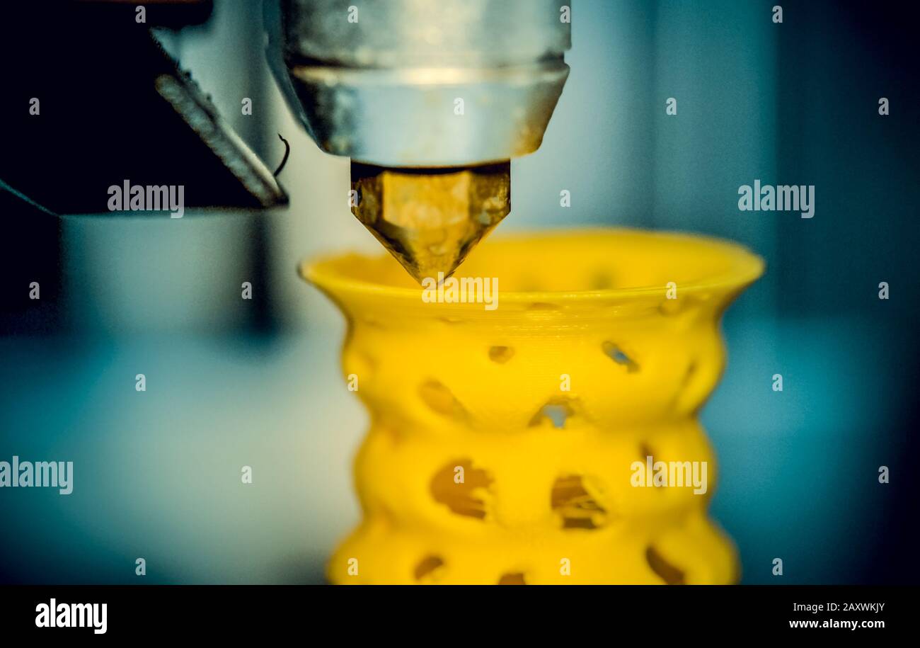 3D printer prints from the plastic figure closeup. 3D printer makes ...