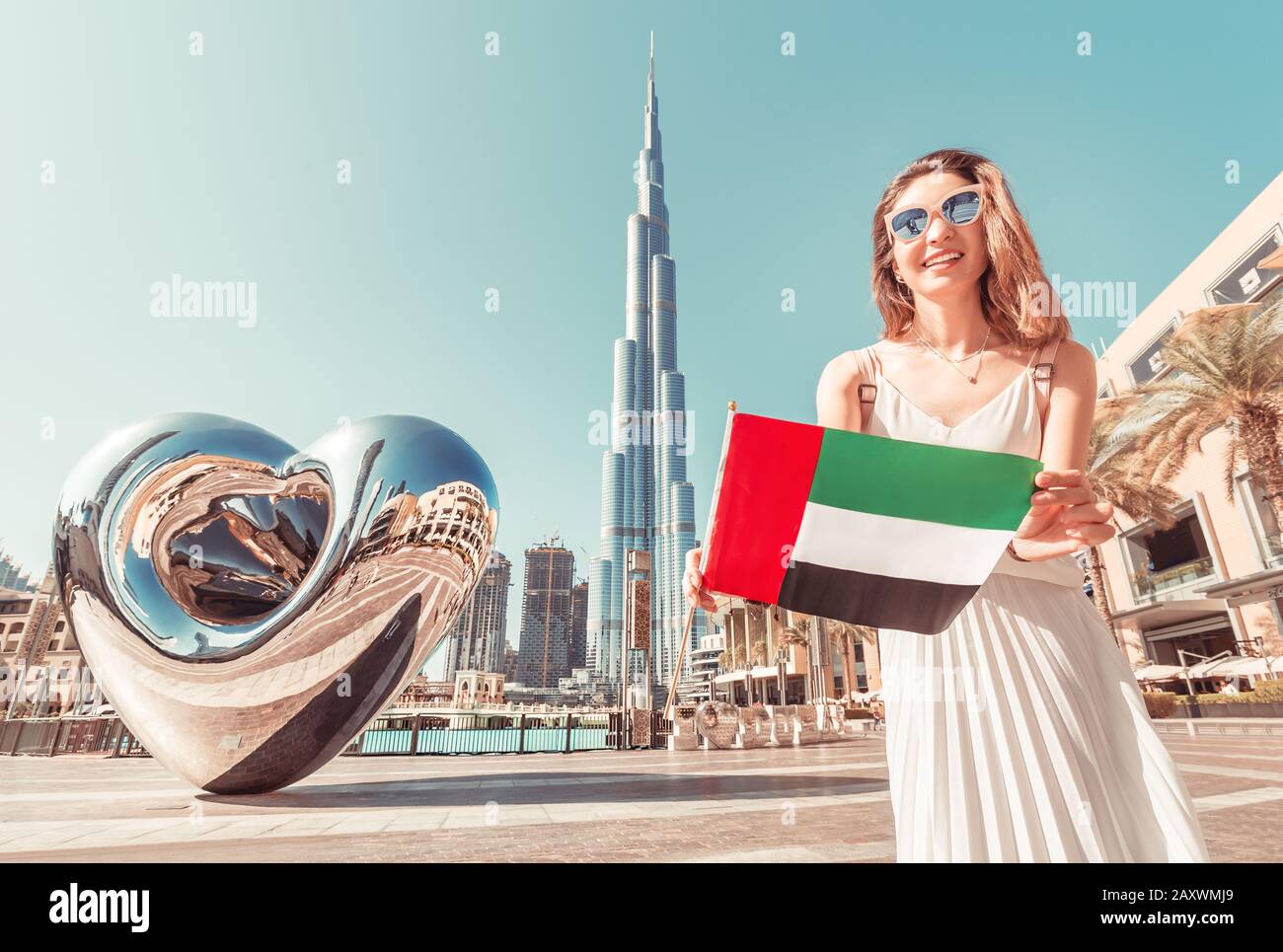 Happy girl with the flag of the UAE on the square near the Dubai Mall ...