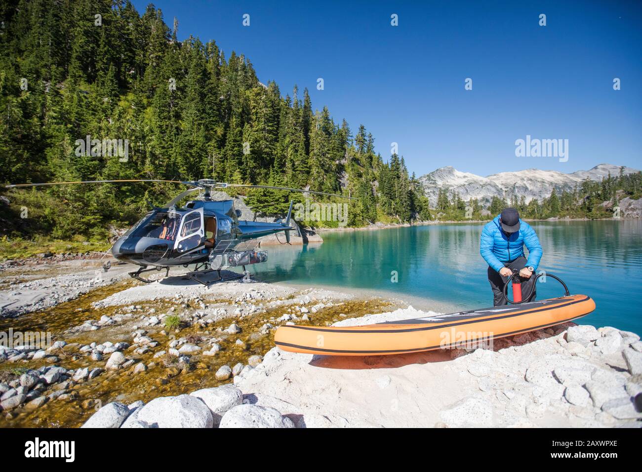 Adventurous man pumps up inflatable SUP next to a remote lake Stock ...