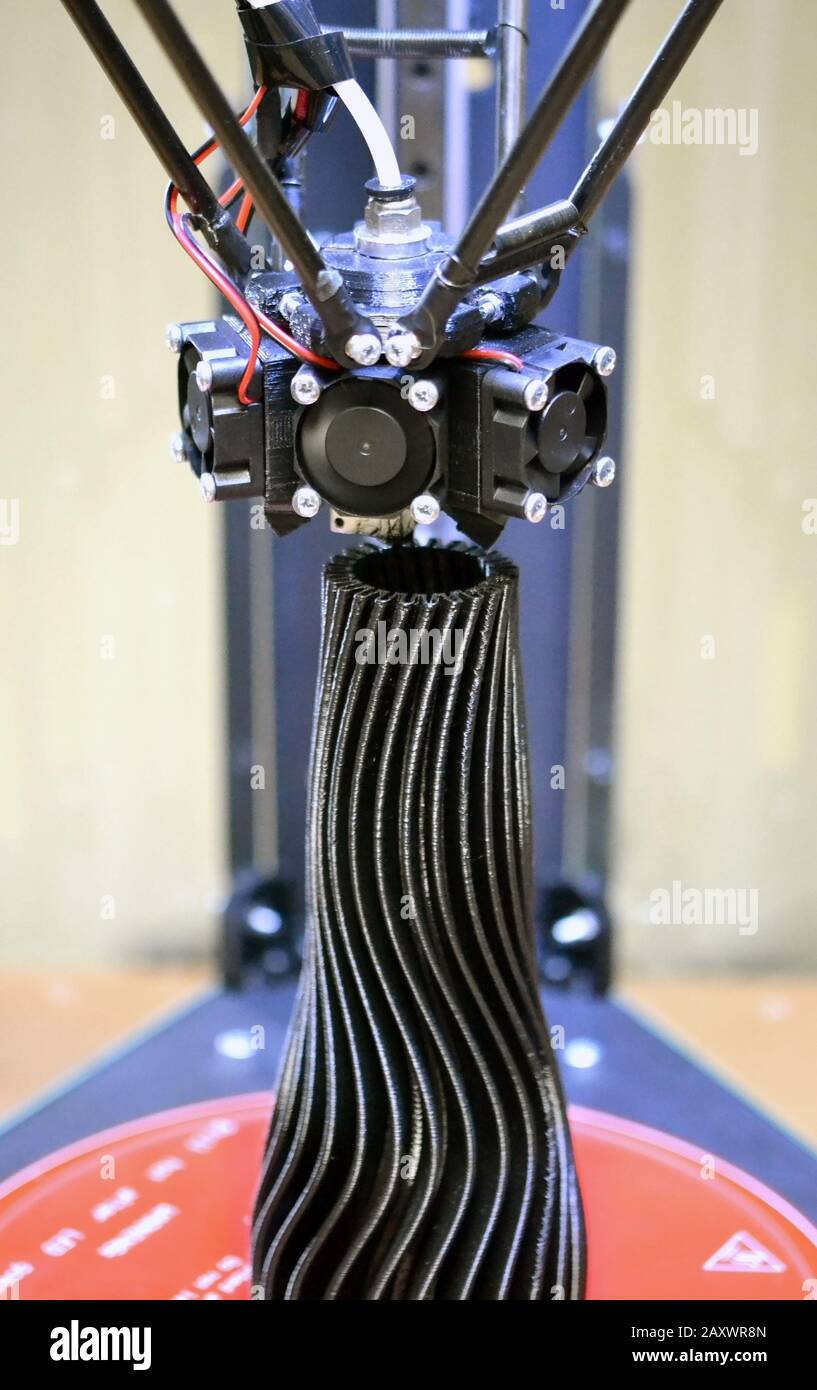 The three-axis 3d printer creates an object in the form of a black vase ...