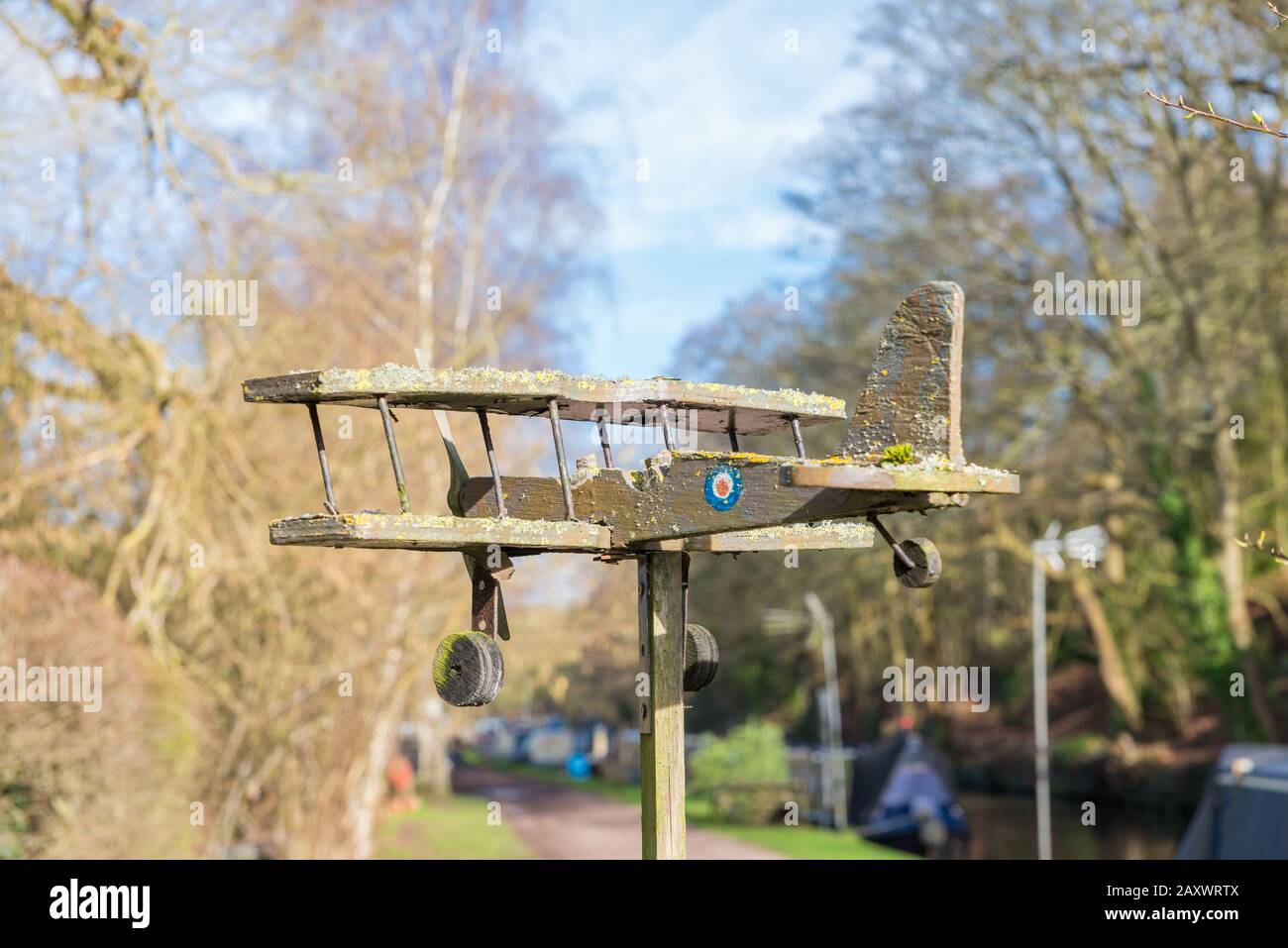 Homemade wooden model biplane mounted on a pole on the towpath on the ...