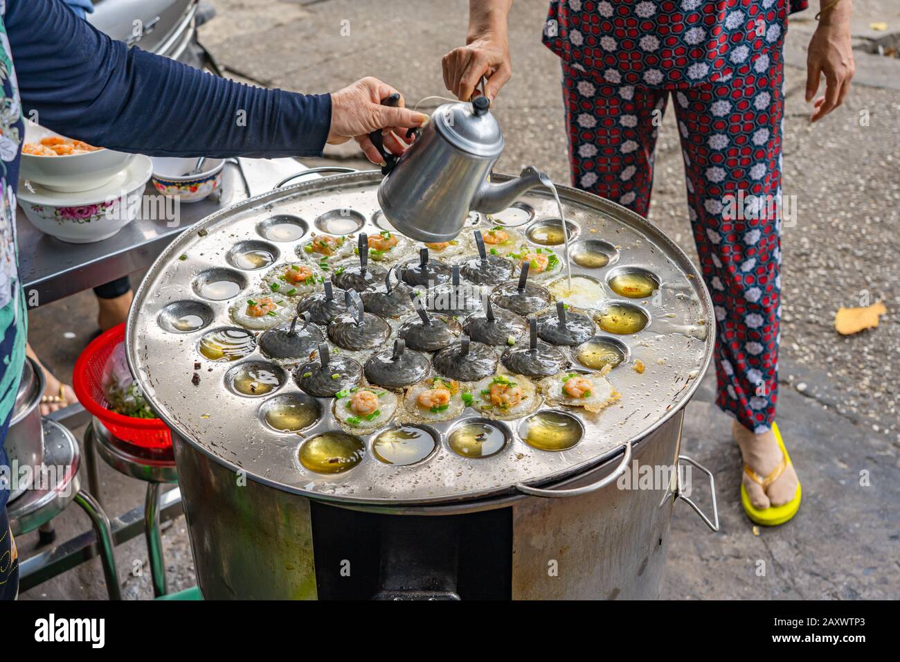 Street food hawker making Vietnamese mini shrimp pancake- Banh Khot ...