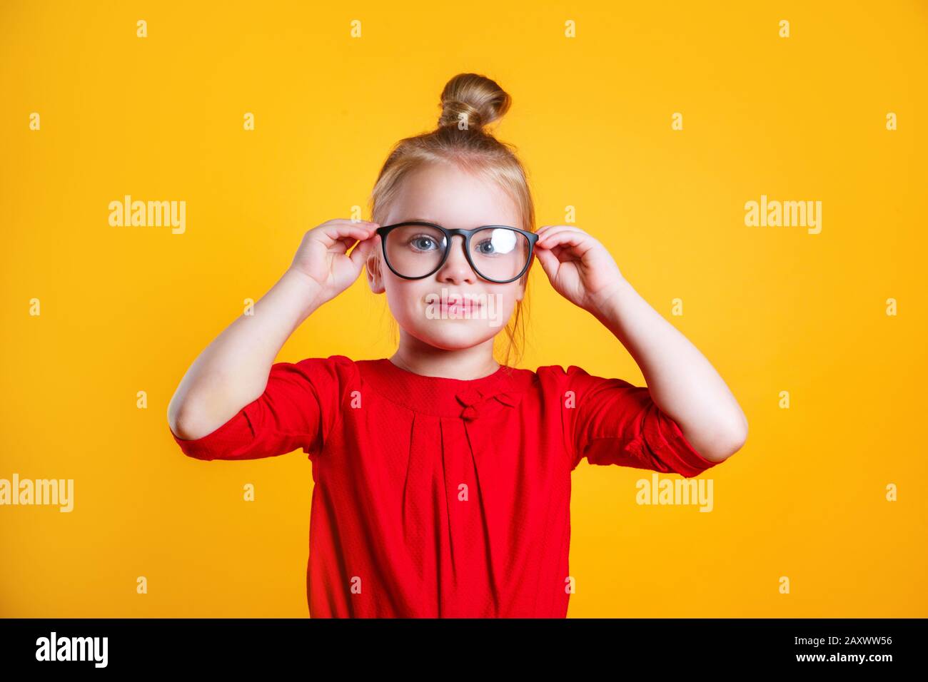 Portrait of smart little girl with glasses on yellow background Stock ...