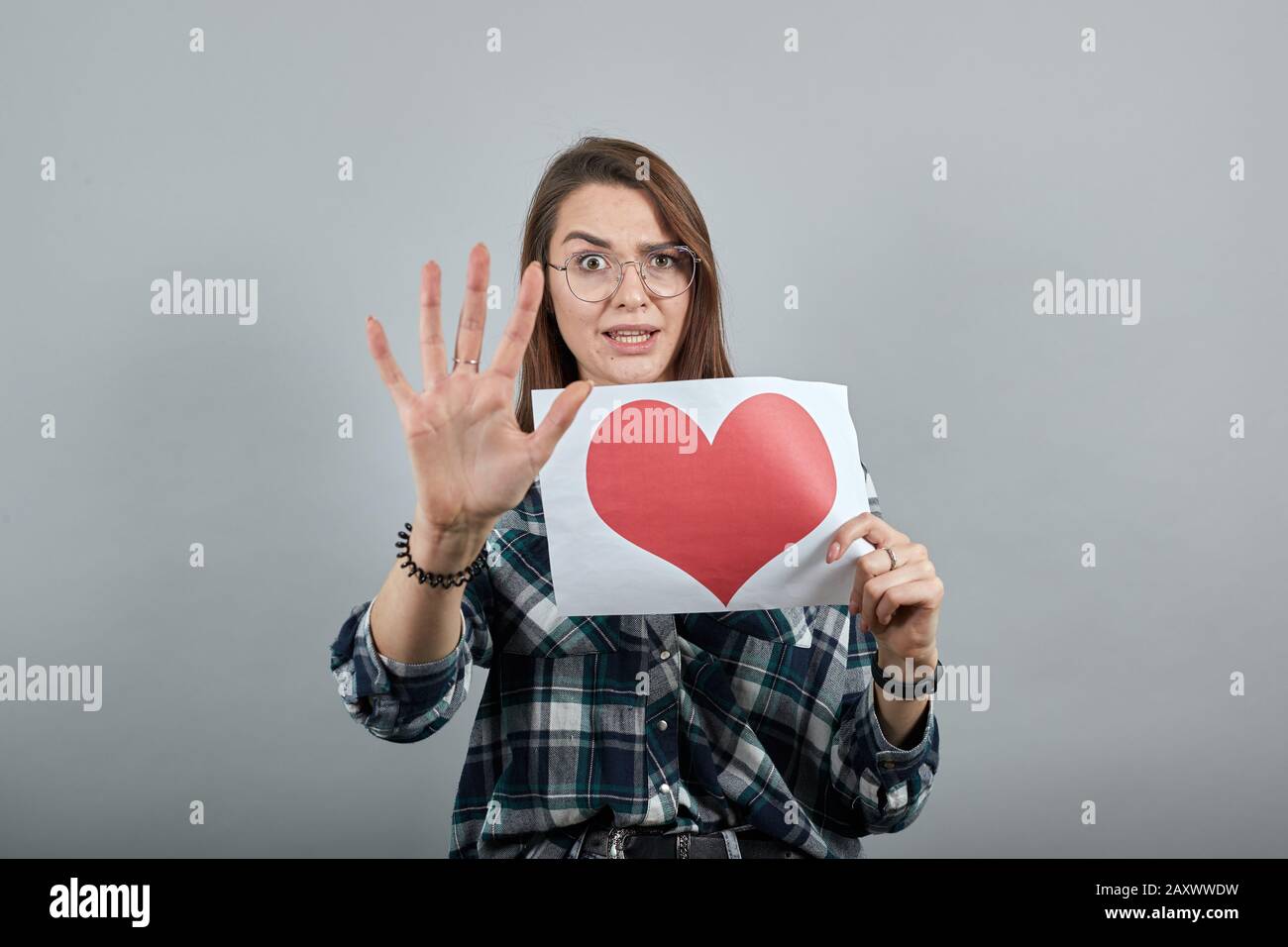 dissenting woman in glasses holds piece of paper with a red heart in ...