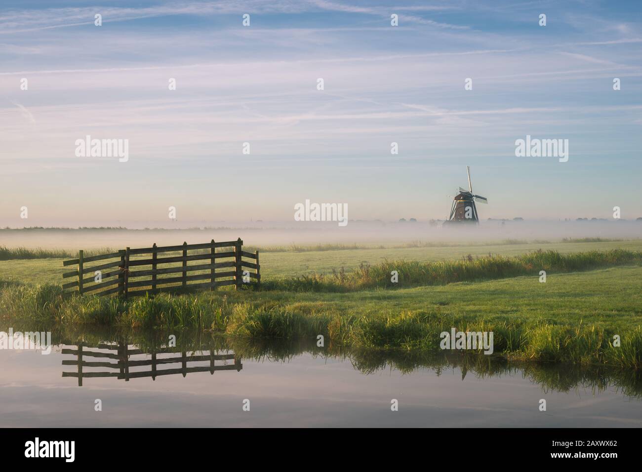 Dutch polder landscape with with windmill that rises above the fog ...