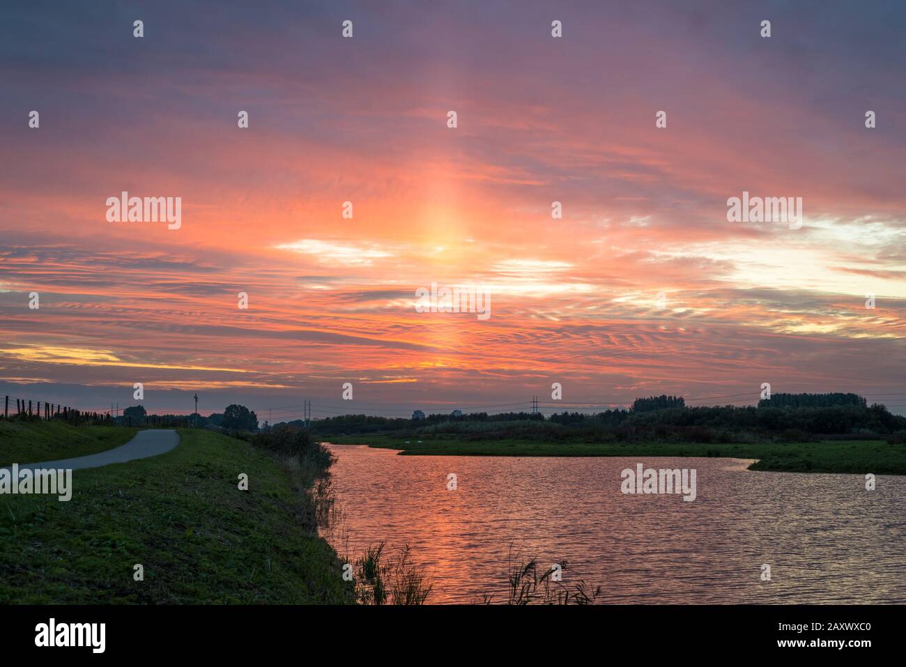 Sun pillar in colorful clouds just after sunset. Atmospheric optical ...