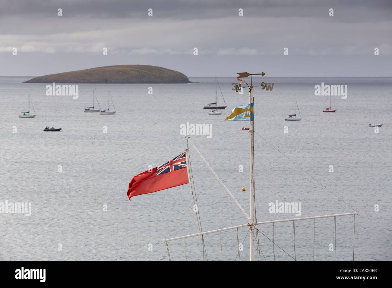Flag pole with weather vane and red ensign fluttering in the wind ...