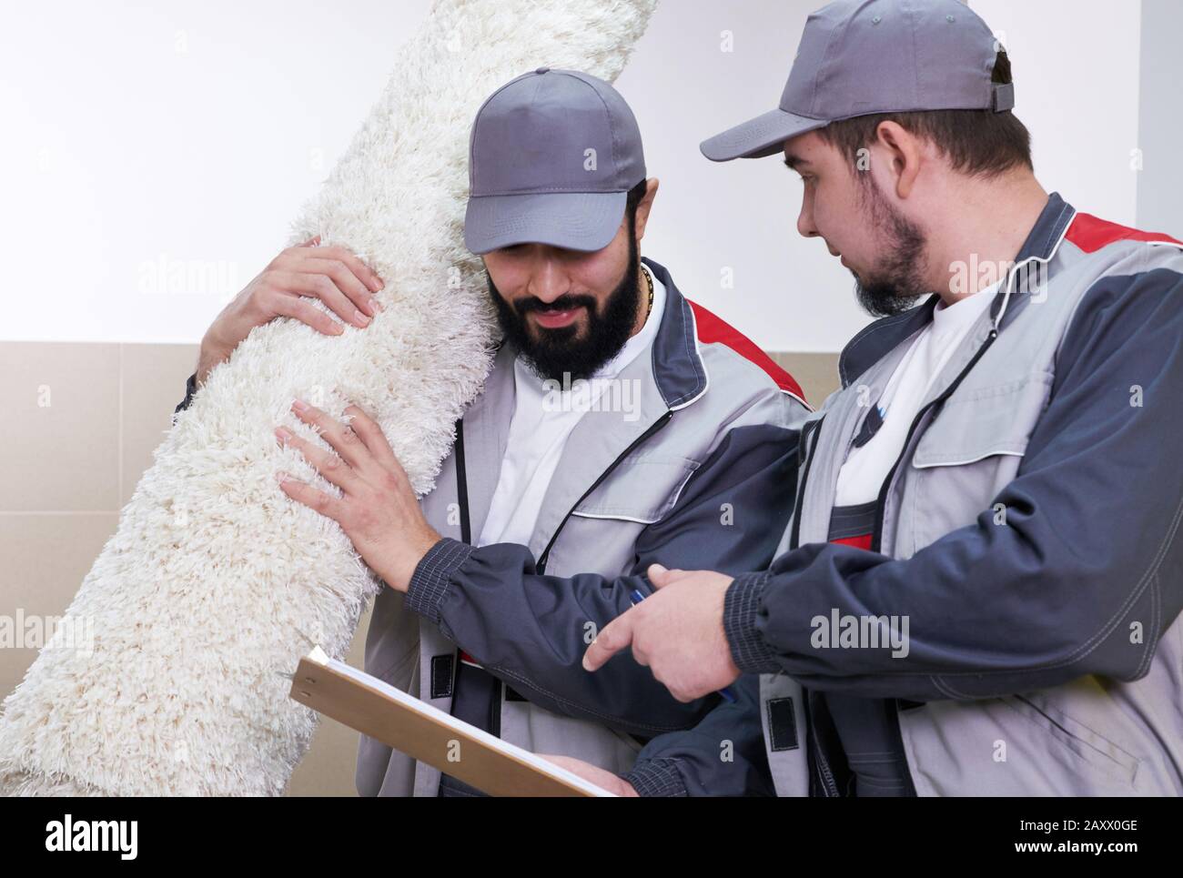 Happy male carrying a carpet in new home Stock Photo - Alamy