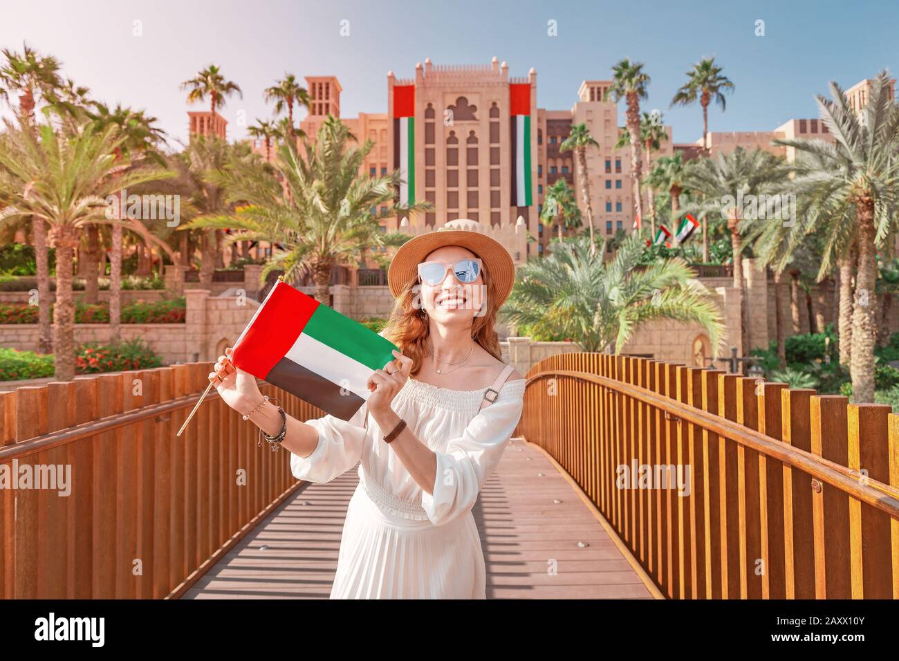 happy girl holding UAE flag and admires beautiful view of the Madinat ...