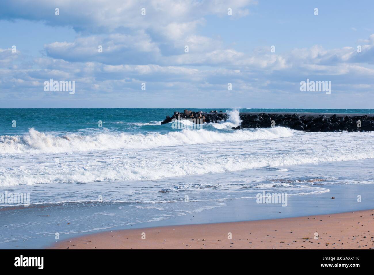 Photo of relaxing ocean waves at the shore with stone dock under cloudy ...