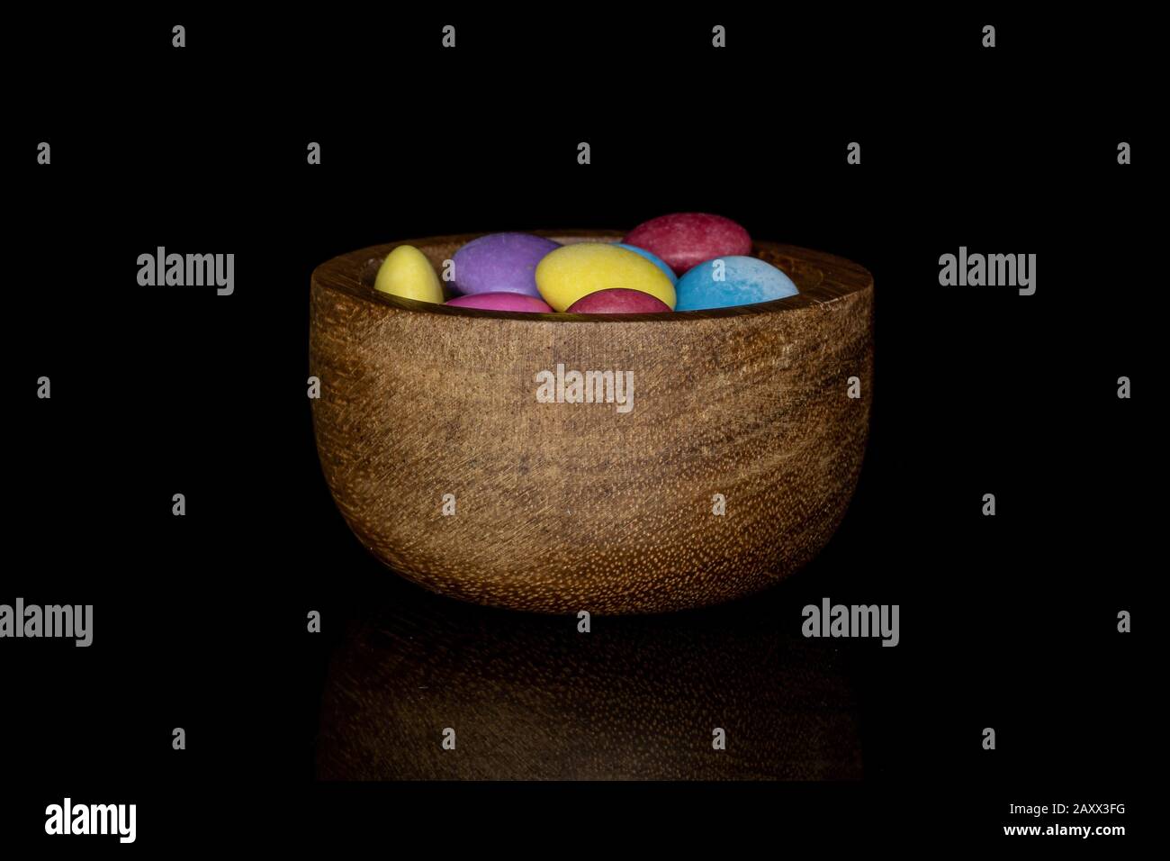 Lot of whole sweet colourful candy in bamboo bowl isolated on black ...
