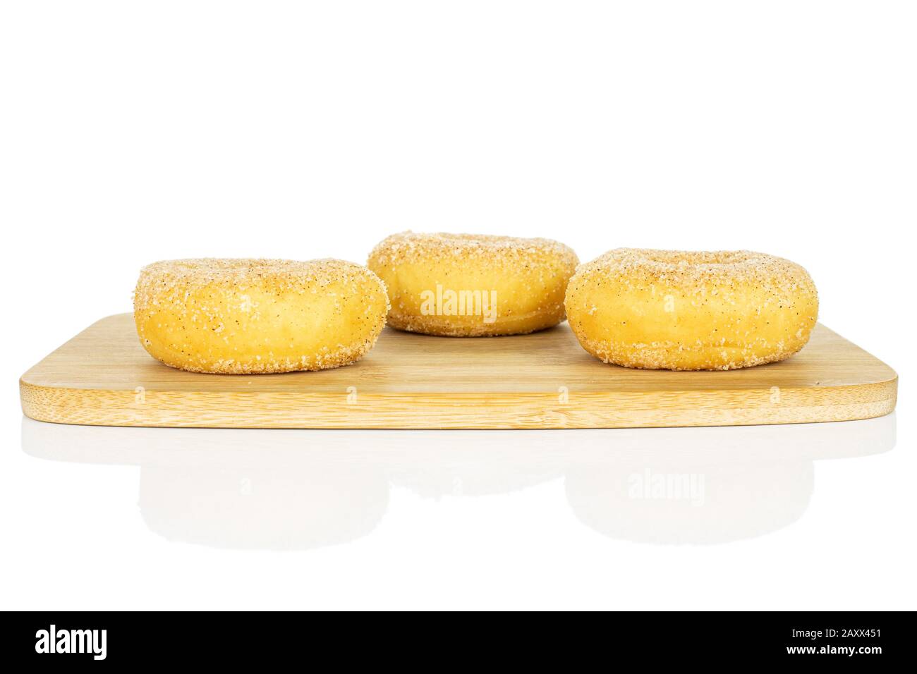 Group of three whole sweet golden mini cinnamon donut on bamboo cutting ...