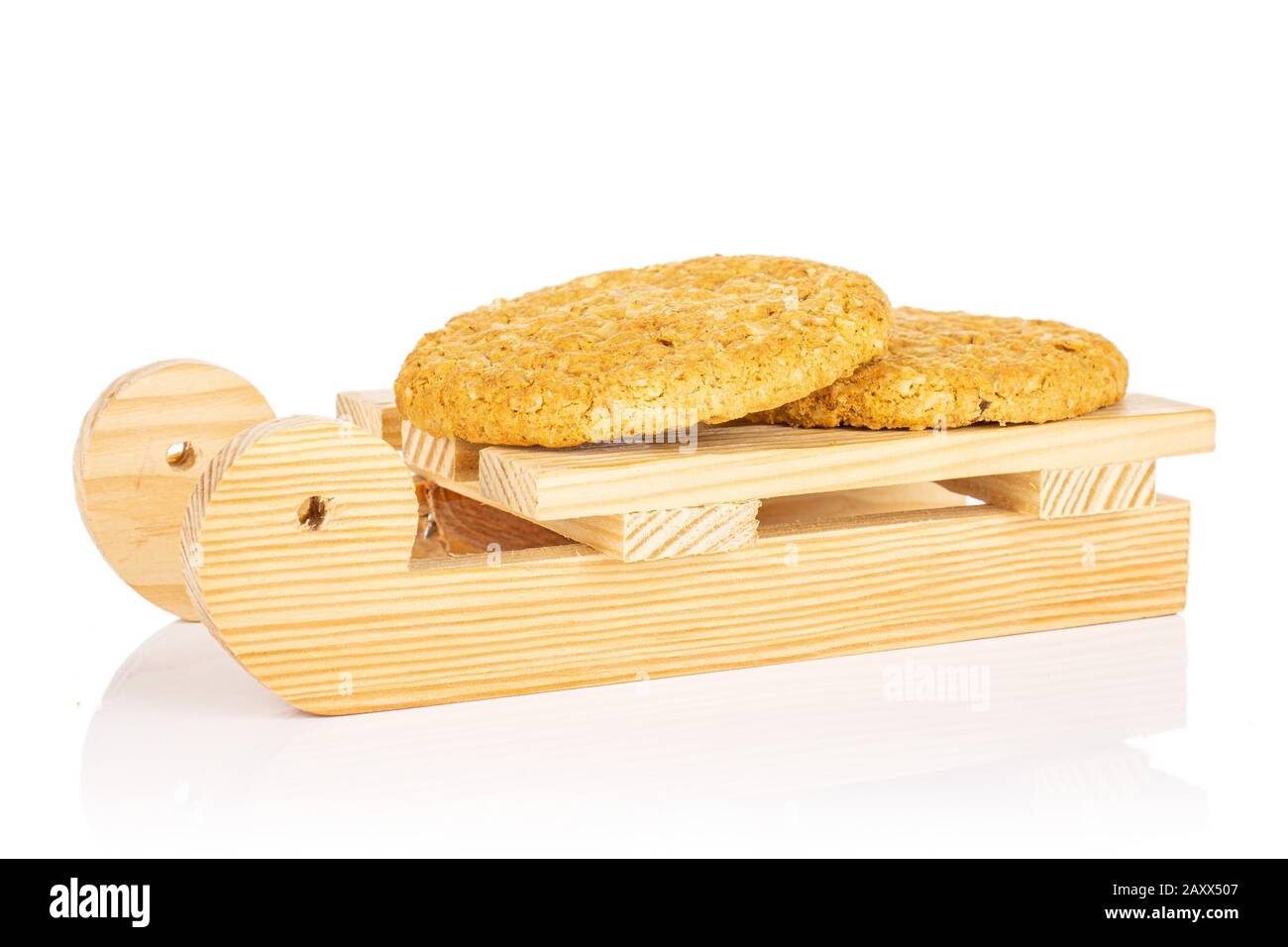 Group of two whole sweet golden oat cookie with wooden sledge isolated ...
