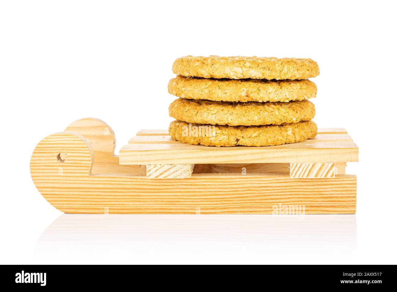 Group of four whole sweet golden oat cookie with wooden sledge isolated ...