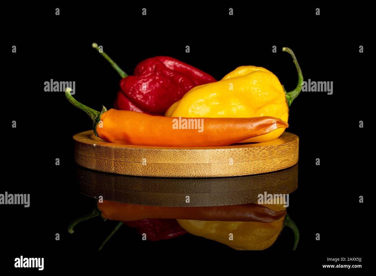 Group of three whole hot chili pepper on bamboo coaster isolated on ...