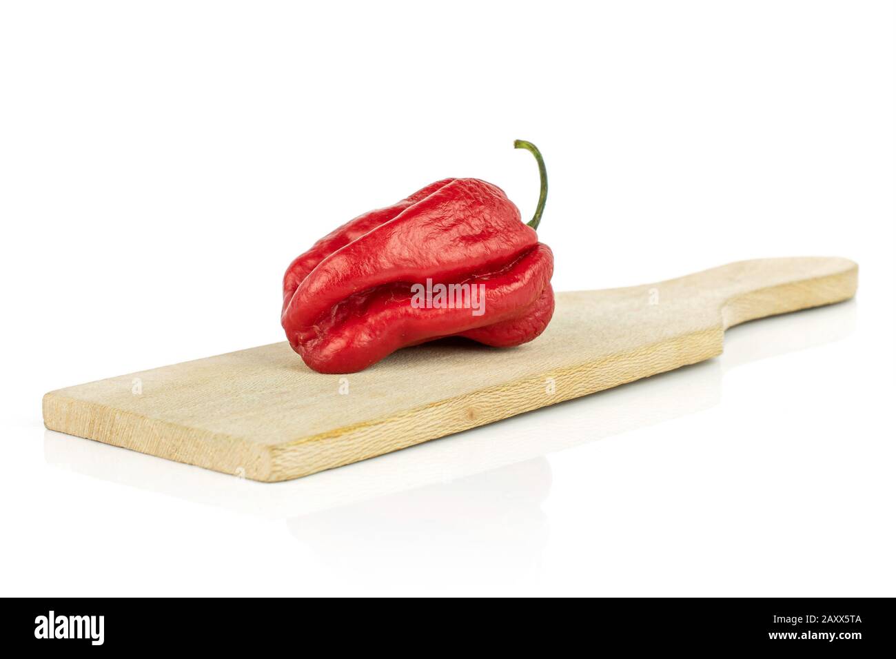 One whole hot chili pepper on small wooden cutting board isolated on ...