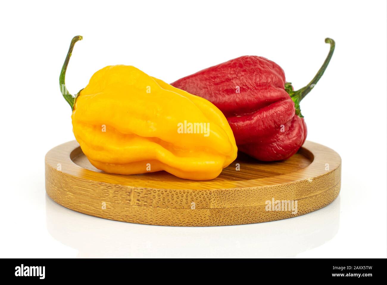 Group of two whole hot chili pepper on bamboo coaster isolated on white ...