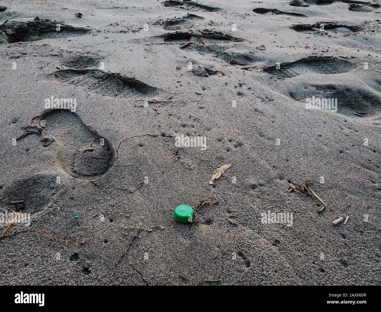 Plastic bottle cork and human footprints on sandy sea ecosystem ...