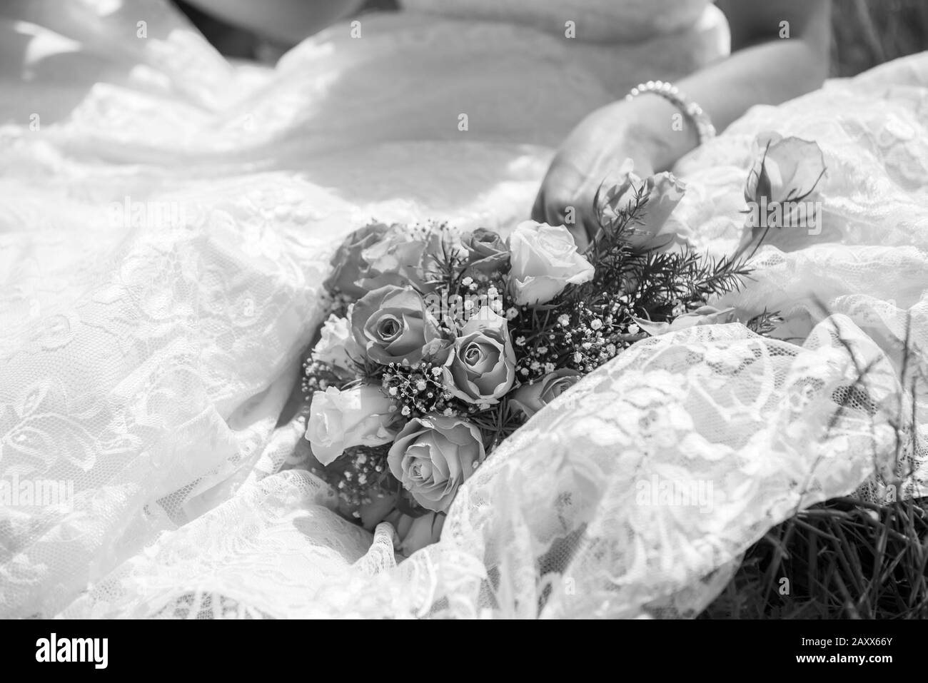Bride sitting down with bouquet on her dress in black and white Stock ...