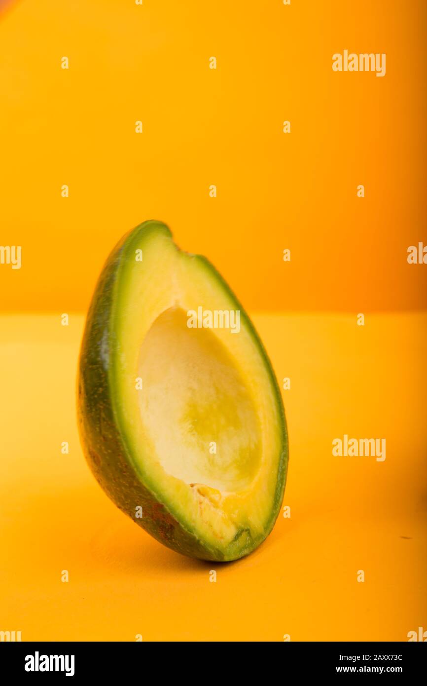 Half avocado isolated in yellow background Stock Photo - Alamy