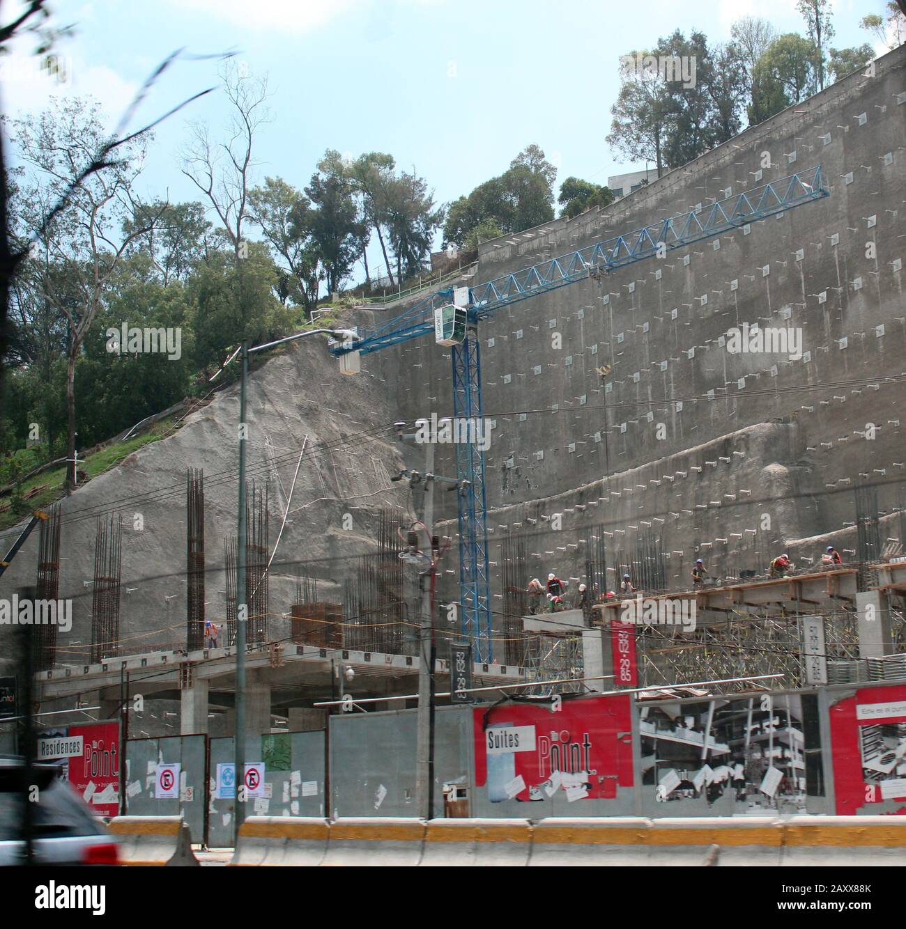 Construction workers structurally enhancing a cement wall cut into a ...
