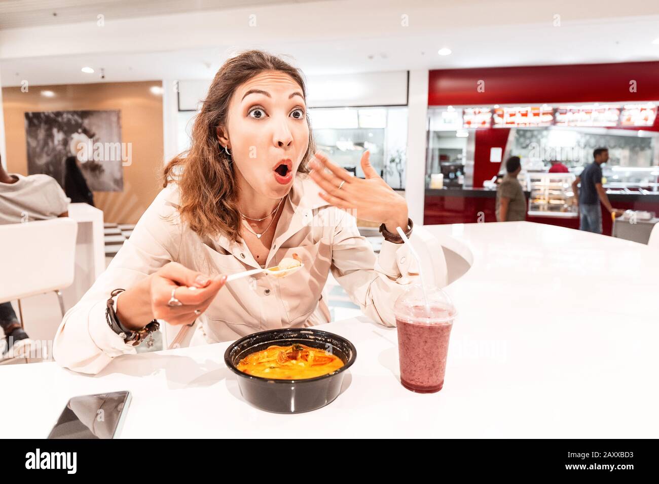 A woman eating too hot and peppery soup in an Asian fast food ...