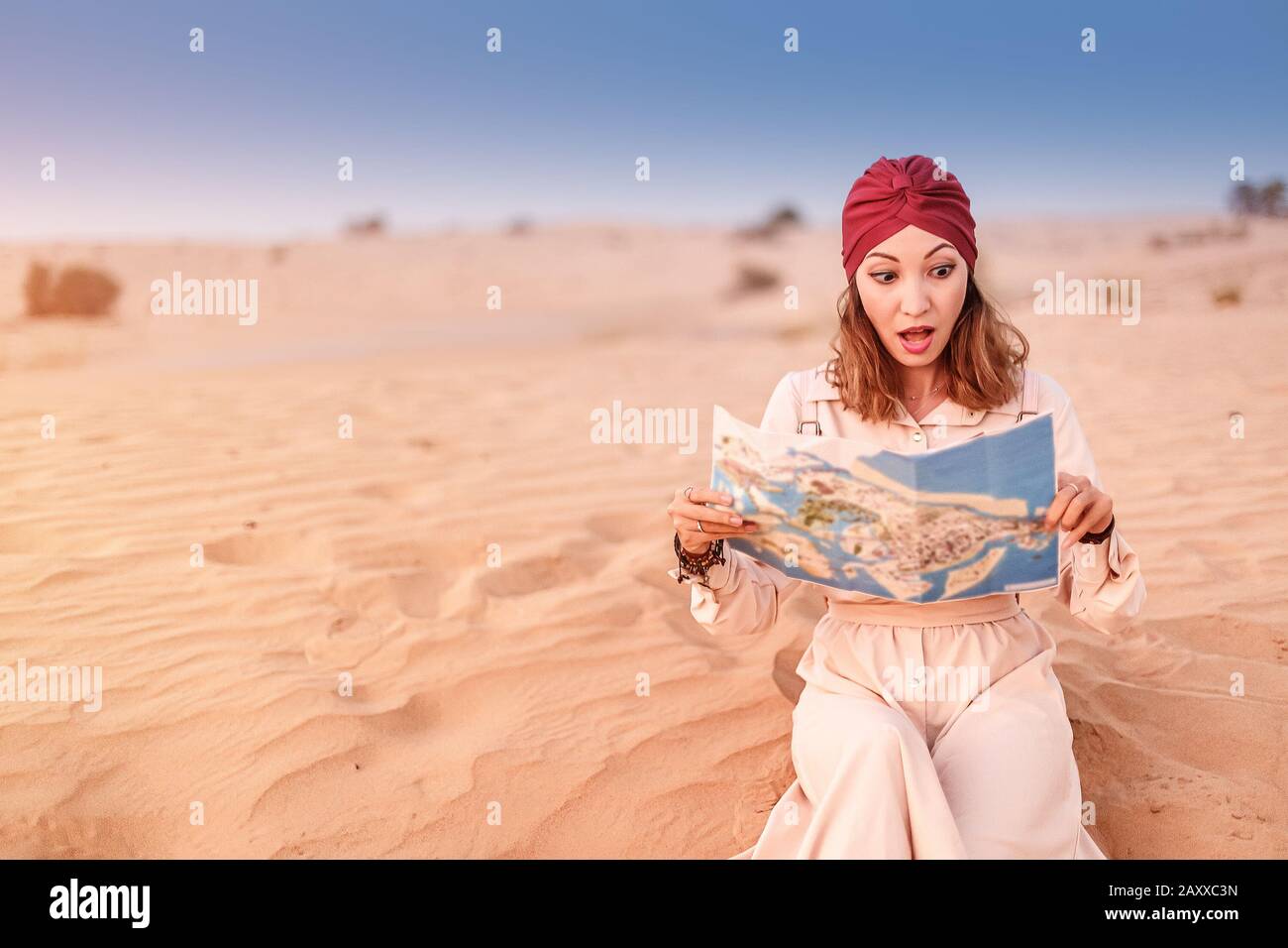 Asian woman wearing turban reading map in Sahara desert in Africa ...