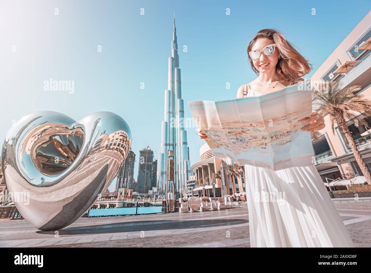 Happy girl looking for interesting places on the map in Dubai. Tourism ...