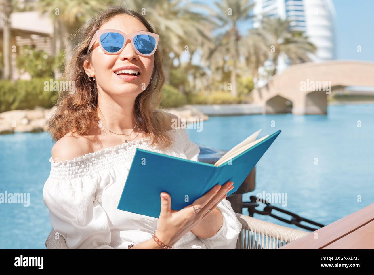 Smiling girl reads menu at the bar or restaurant on the terrace while ...