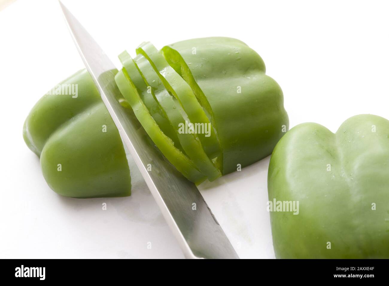 Cut green pepper with knife on white background Stock Photo - Alamy