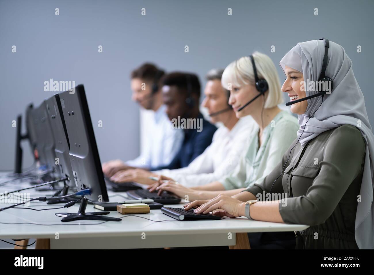 Positive Female Customer Services Agent With Headset Working In A Call ...