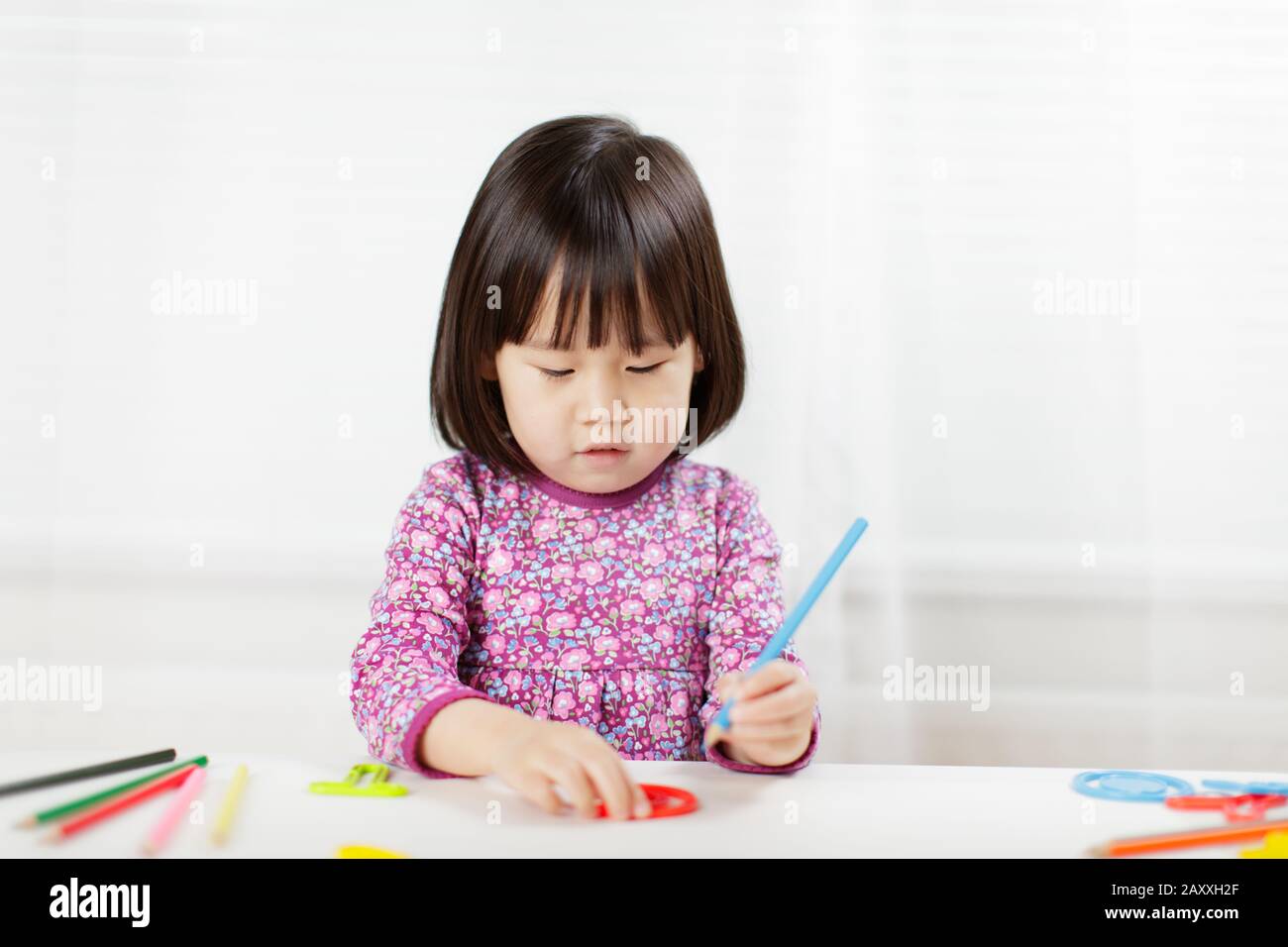 toddler girl practice writing letters on white paper against white ...