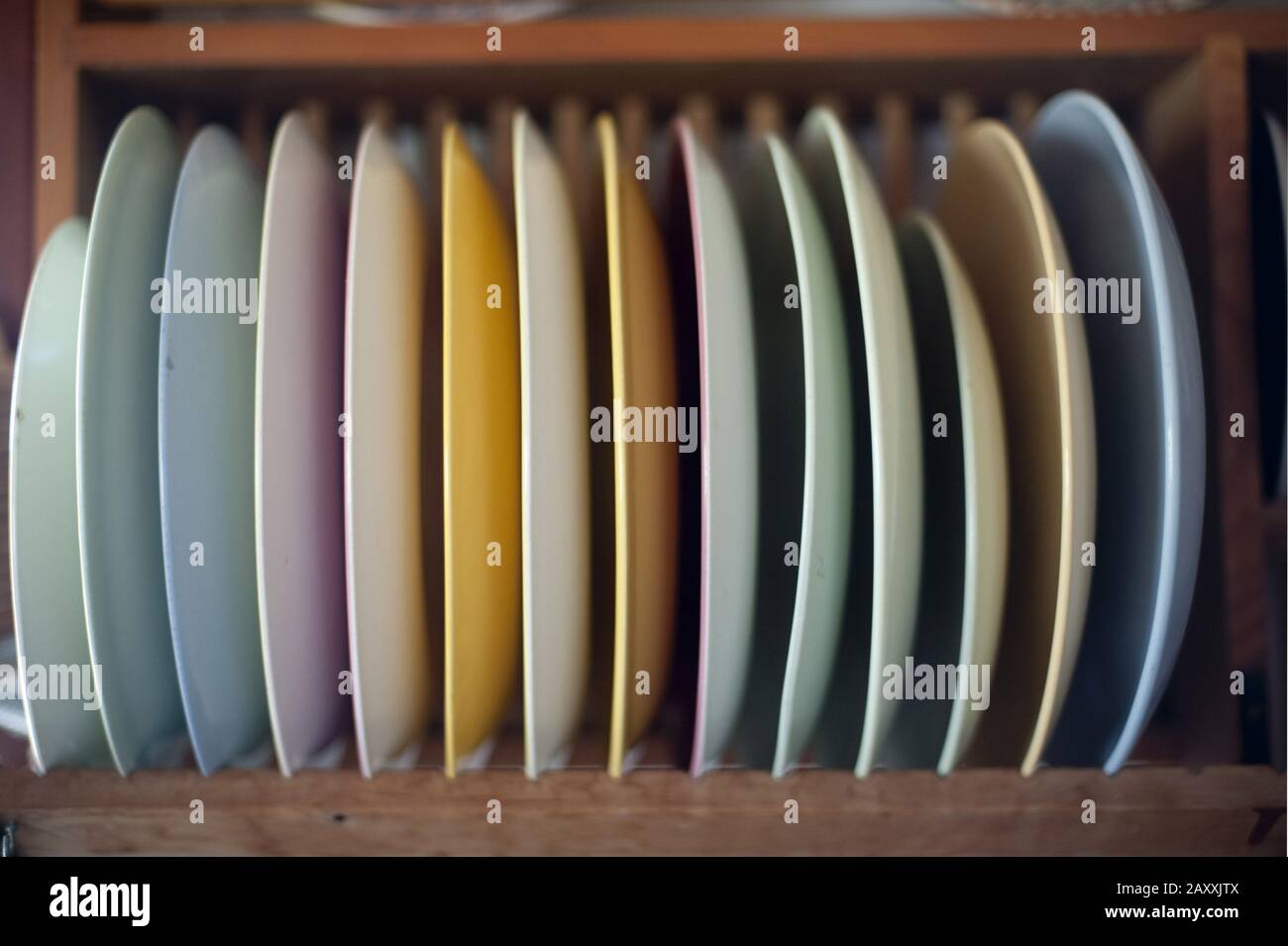 Selection of clean colourful dinner plates in a wooden rack mounted on ...