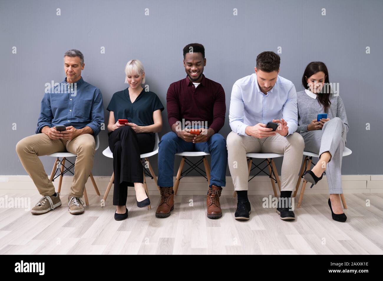 Business People Sitting On Chairs Using Smartphones In Office Stock ...