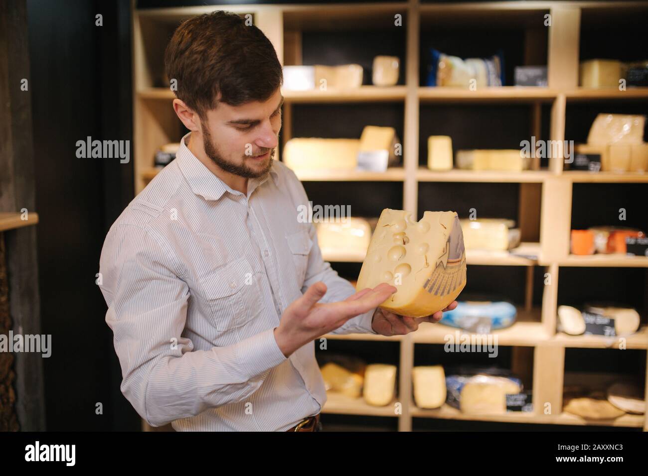 Hansome man hold big slice of cheese maasdam in hand. Cheese with big ...