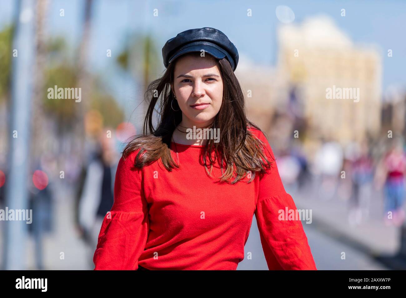 Front view of a beautiful young woman wearing urban clothes sitting on ...