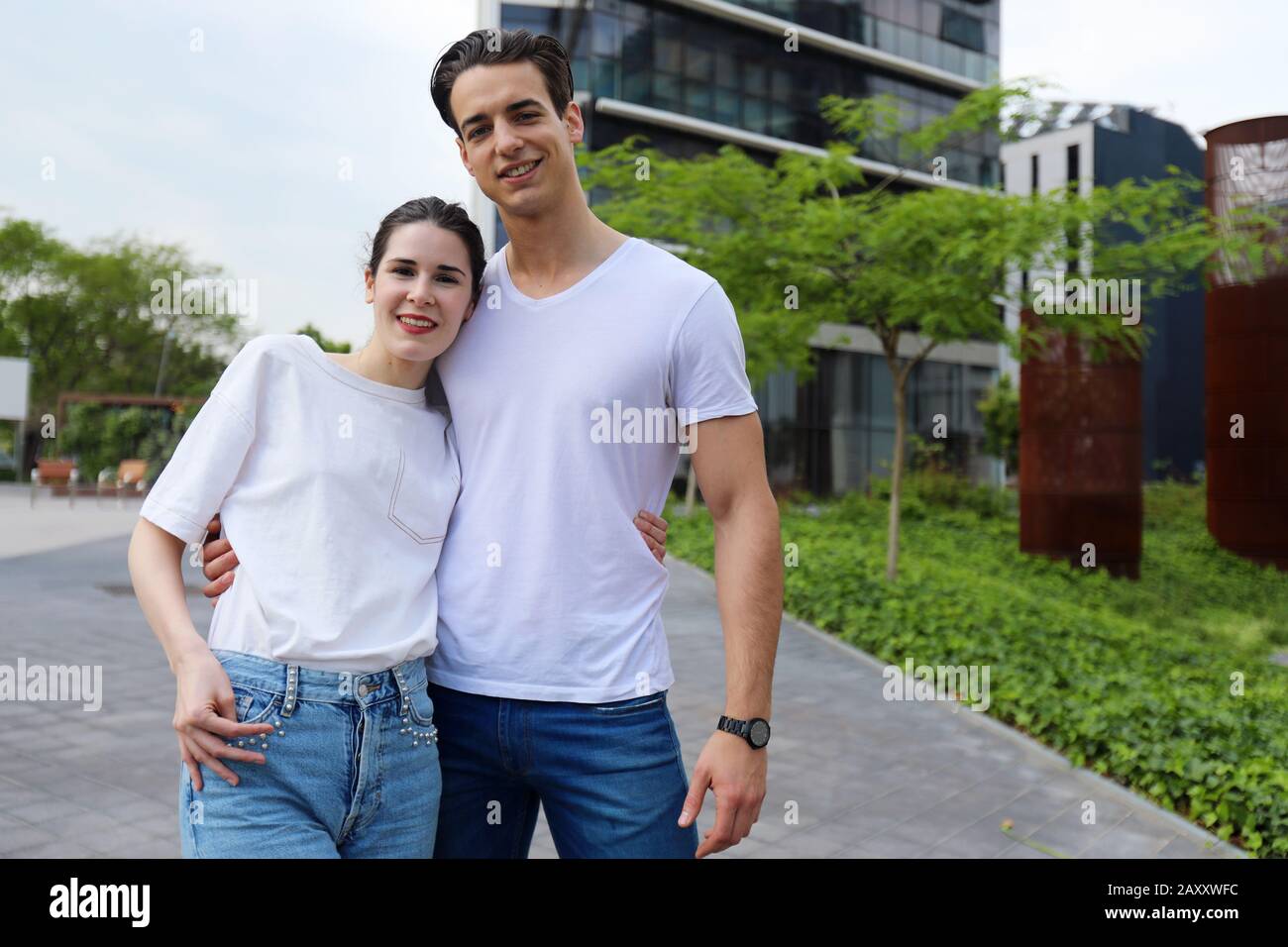 Beautiful young couple hugging, looking at camera and smiling while ...