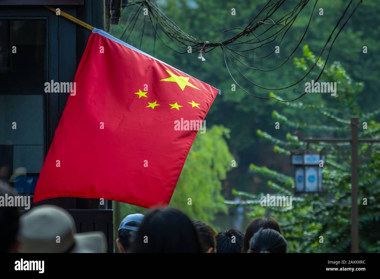 Chinese flag flutering above narrow street in the Old town of Fenghuang ...