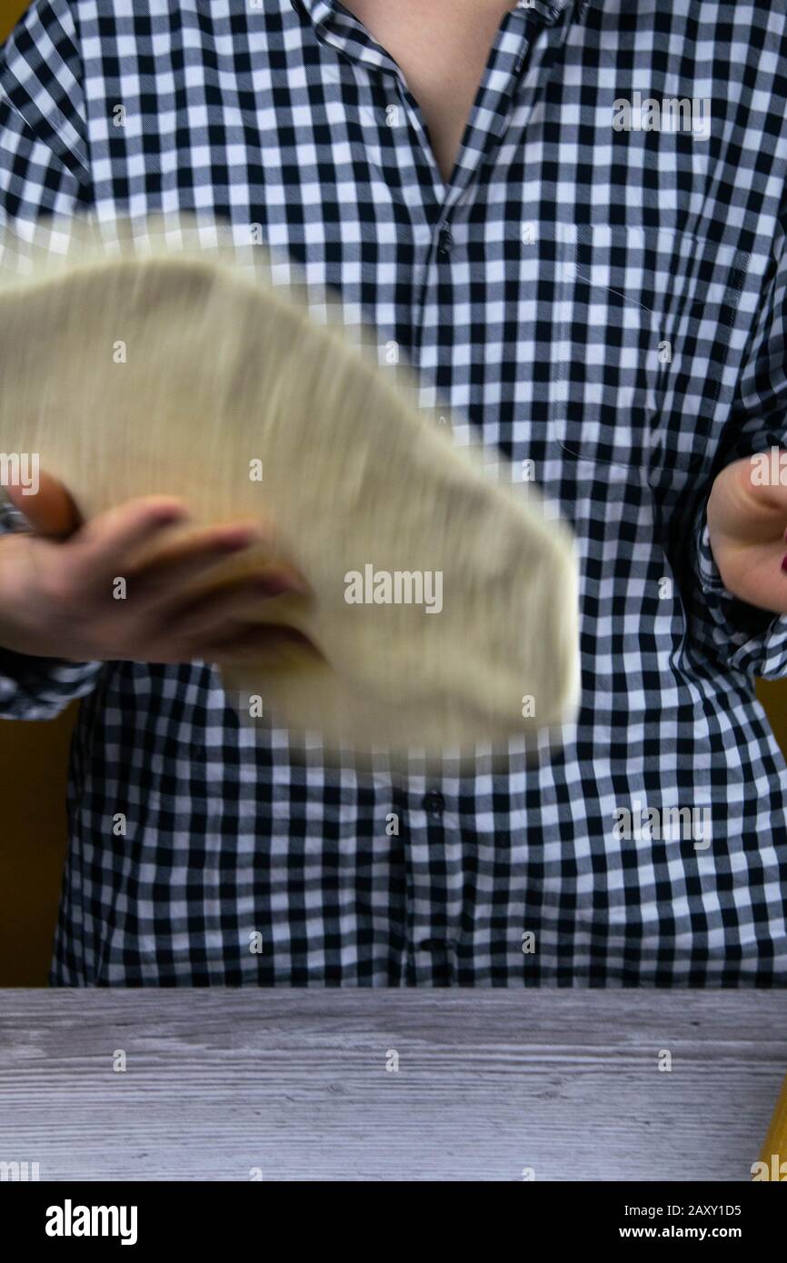Woman tossing a slice of pizza dough. Fresh original italian raw pizza ...