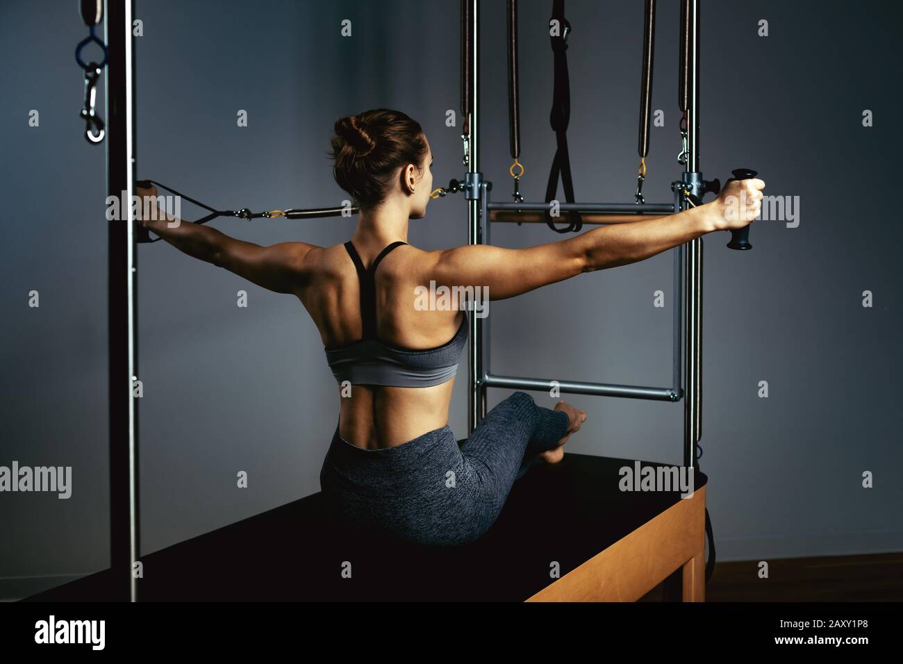 Young girl doing pilates exercises with a reformer bed. Beautiful slim ...