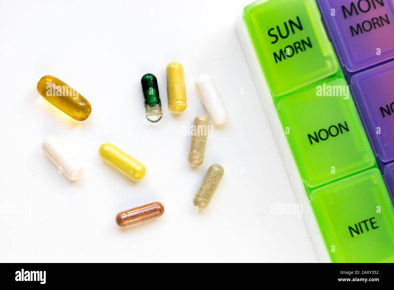 Assortment of 10 capsules with green and purple weekly pill container ...