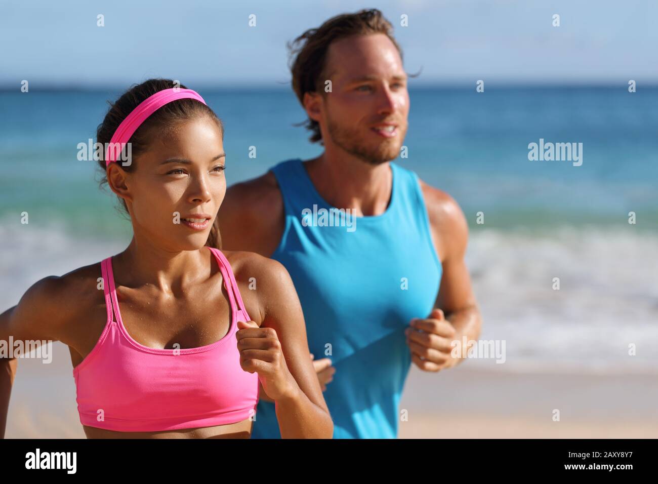 Couple runners running on beach. Interracial young adults asian woman ...